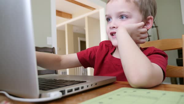 A cute little boy using the computer to do his preschool learning ...
