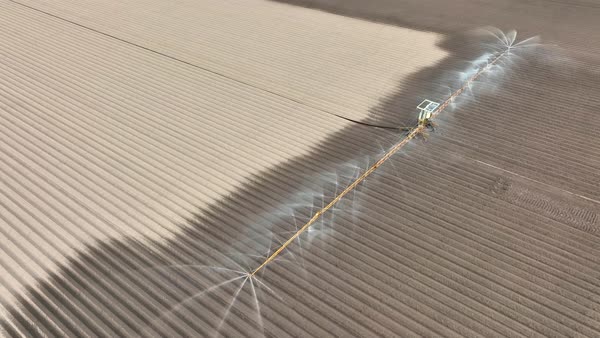 Irrigation overhead sprinkler machine spraying water on a field during ...