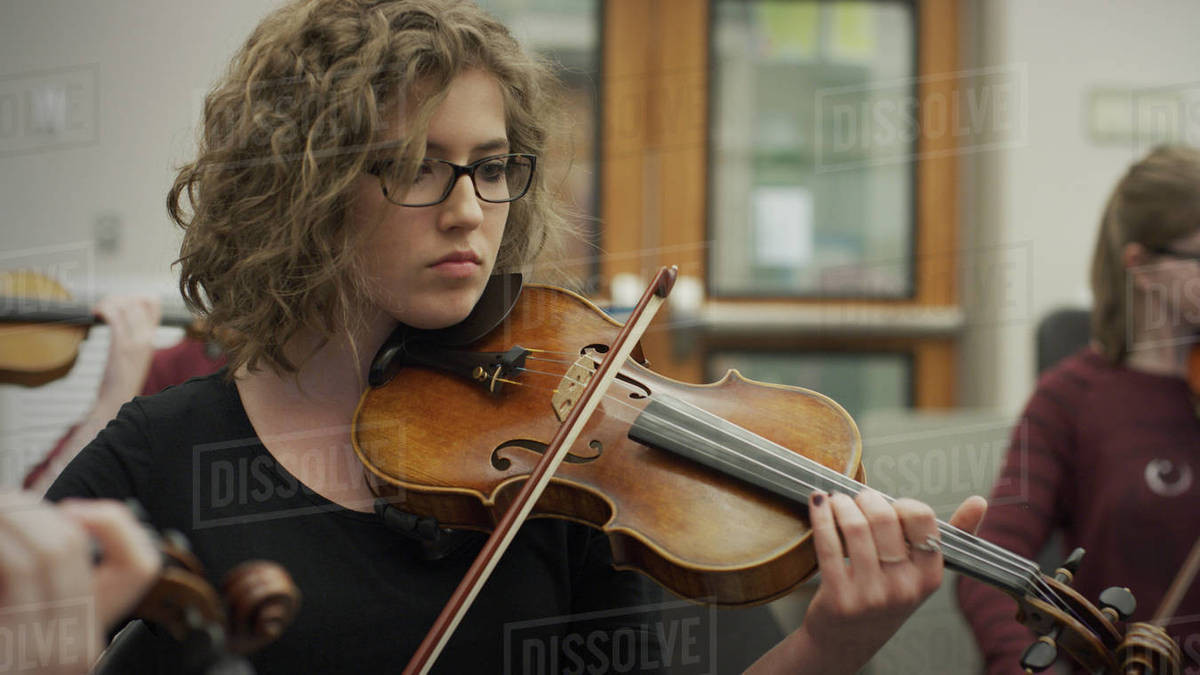 Serious teenage girl musician playing violin in band class - Stock ...