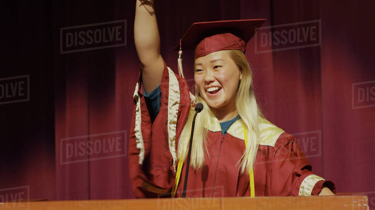 Cheering student speaking at podium on stage during graduation ceremony ...