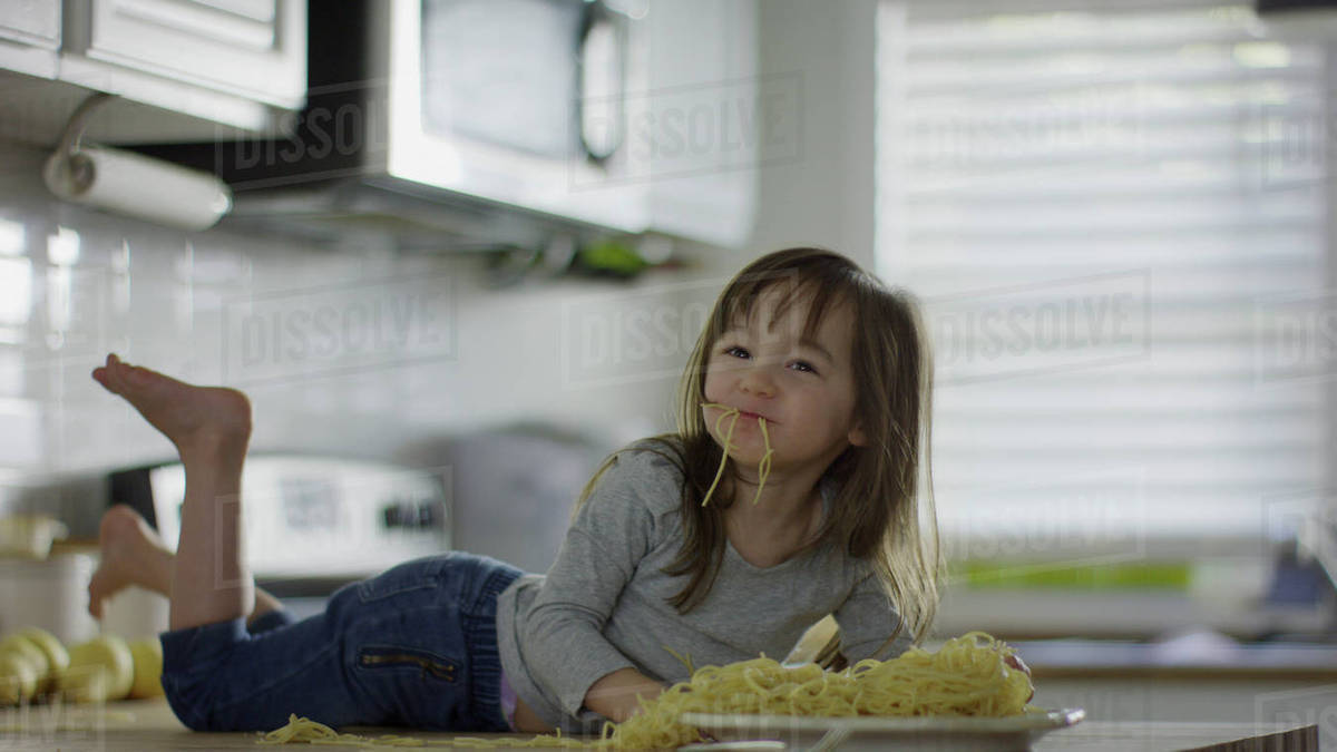 Naughty messy girl laying on kitchen counter eating plate of spaghetti ...