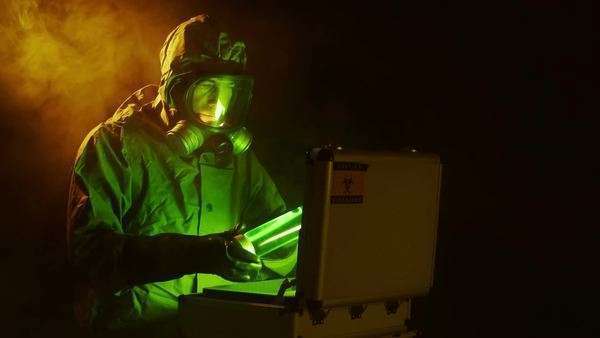A man dressed in military grade hazmat suit places a biohazard sample ...