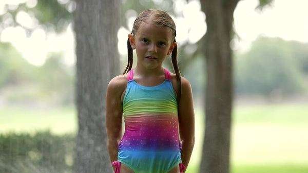A sweet little girl with blond ponytails and a colorful bathing suit ...