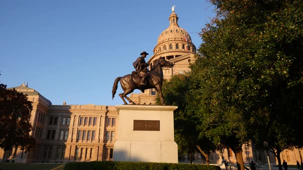 The dome of the Texas State Capitol building rises above a statue of a ...