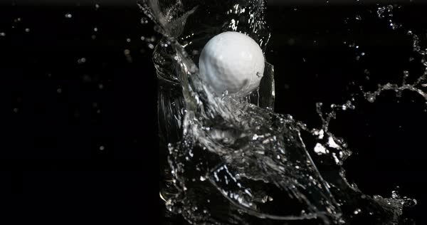 Golf ball falling into water against black background - 4K Royalty-free ...