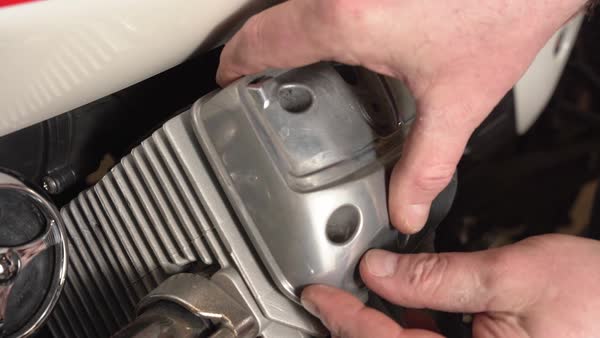 Installing the valve cover on the motorcycle engine. The mechanic ...
