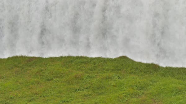 Loop of water jet falling down from the waterfall,grass field in the ...