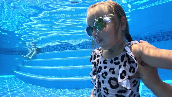 Little girls, sisters, triplets swim in a pool with a mask and snorkel ...