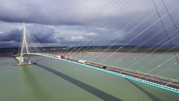 Aerial view of flowing car and truck traffic on a suspension bridge in ...