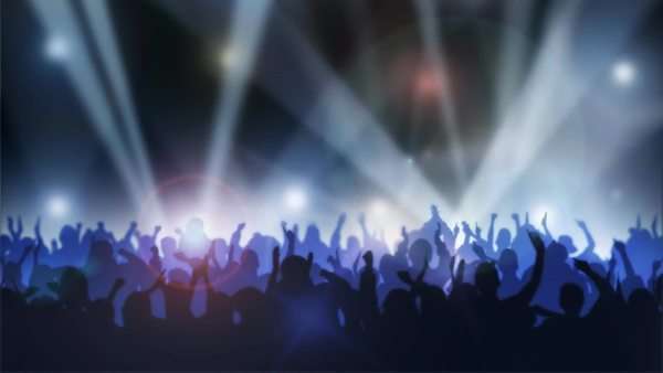 Crowd of cheering silhouettes in a packed arena with spotlights and ...