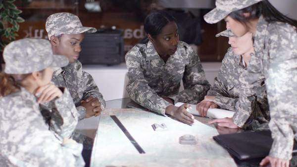 Female military officers in army office, looking at a map and ...