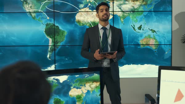 International business team looking at world map graphic on video wall ...