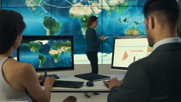 International business team looking at world map graphic on video wall ...