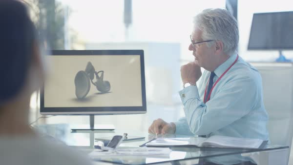 Audiology doctor showing patient a modern hi tech hearing aid and ...