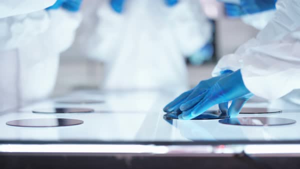 Scientific research team wearing full body suits examining hi-tech ...