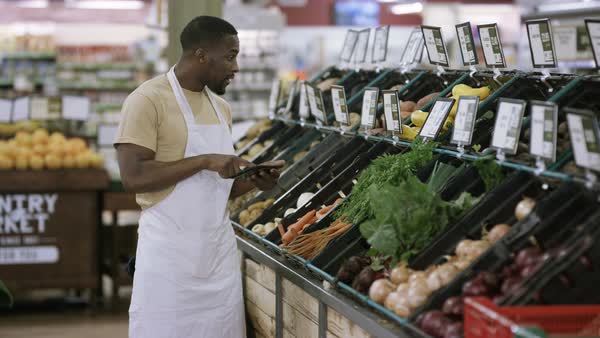 Portrait friendly worker in grocery store turns to smile at camera ...