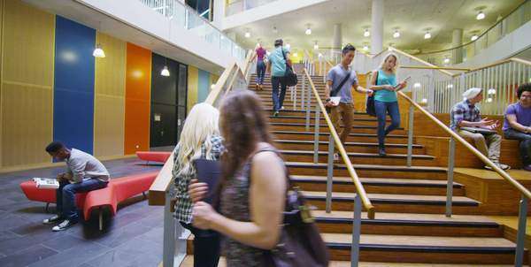 Diverse group of students walking through large contemporary university ...