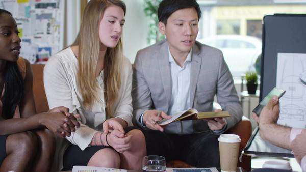 Business team in a meeting, looking at world map on computer tablet ...