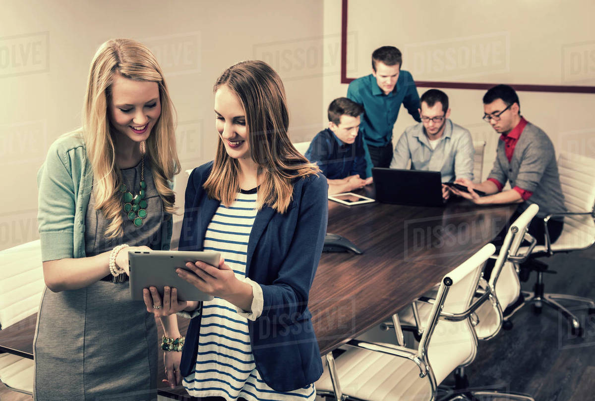 Two young millennial business professionals looking at a pad while ...