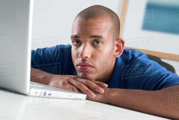Young Man Resting Head On Table With Laptop - Stock Photo - Dissolve