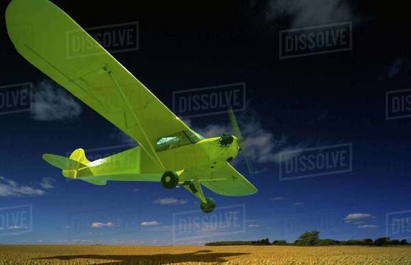 Airplane Flying Low Over Farmland - Stock Photo - Dissolve