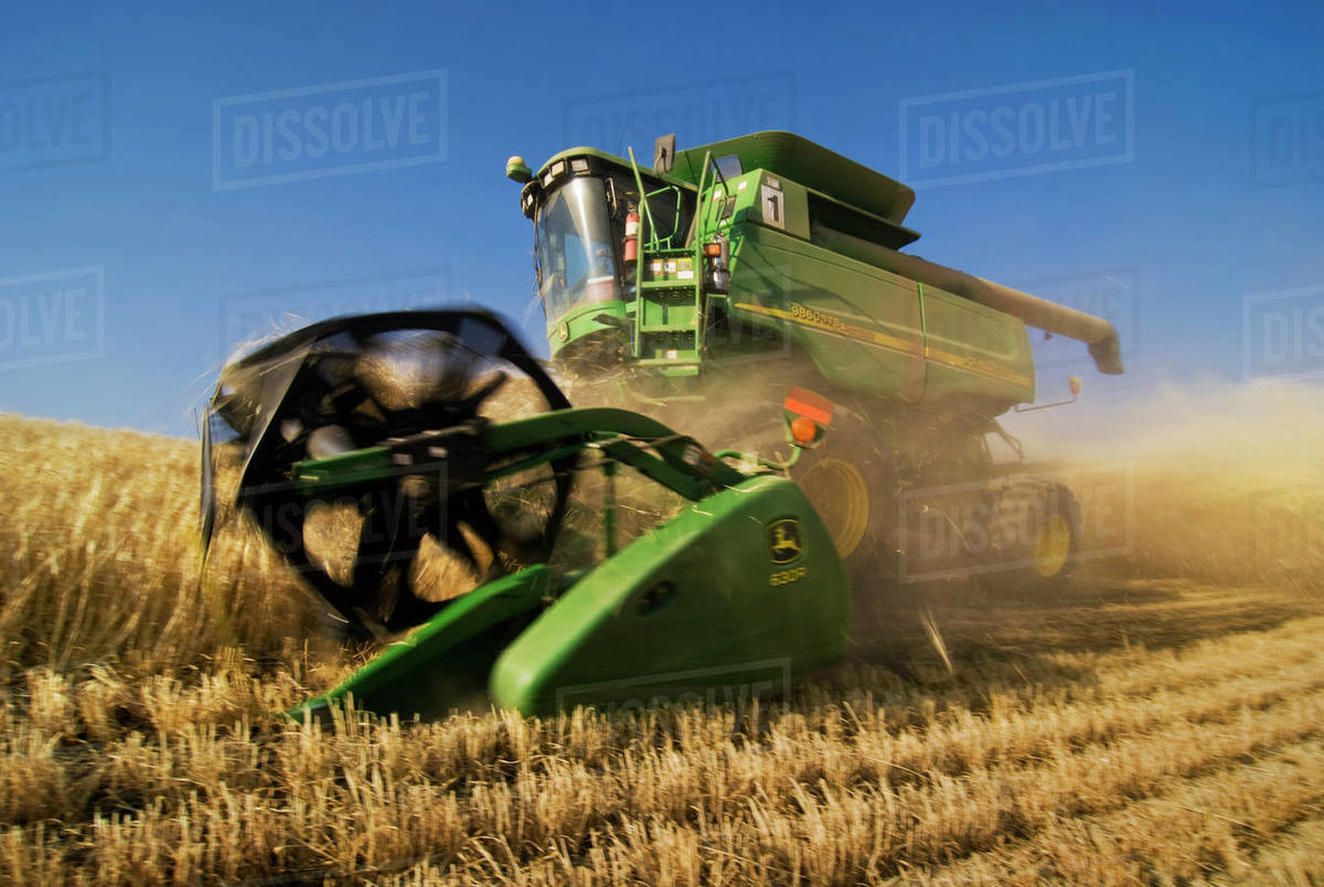 Agriculture - A John Deere combine harvests barley on steep hillside ...