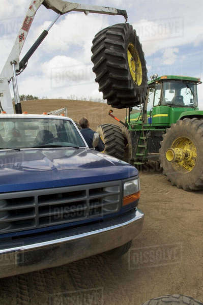 Agriculture - A tire technician works to change a tractor tire in the ...