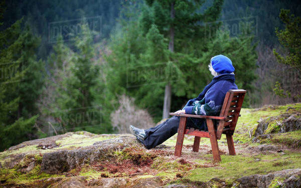 Woman sitting in a chair looking at nature; Bowen Island, British ...