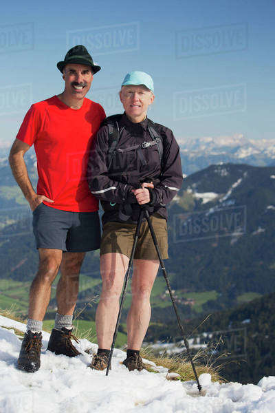 Female and male hiker on top of snow covered mountain with valley below ...