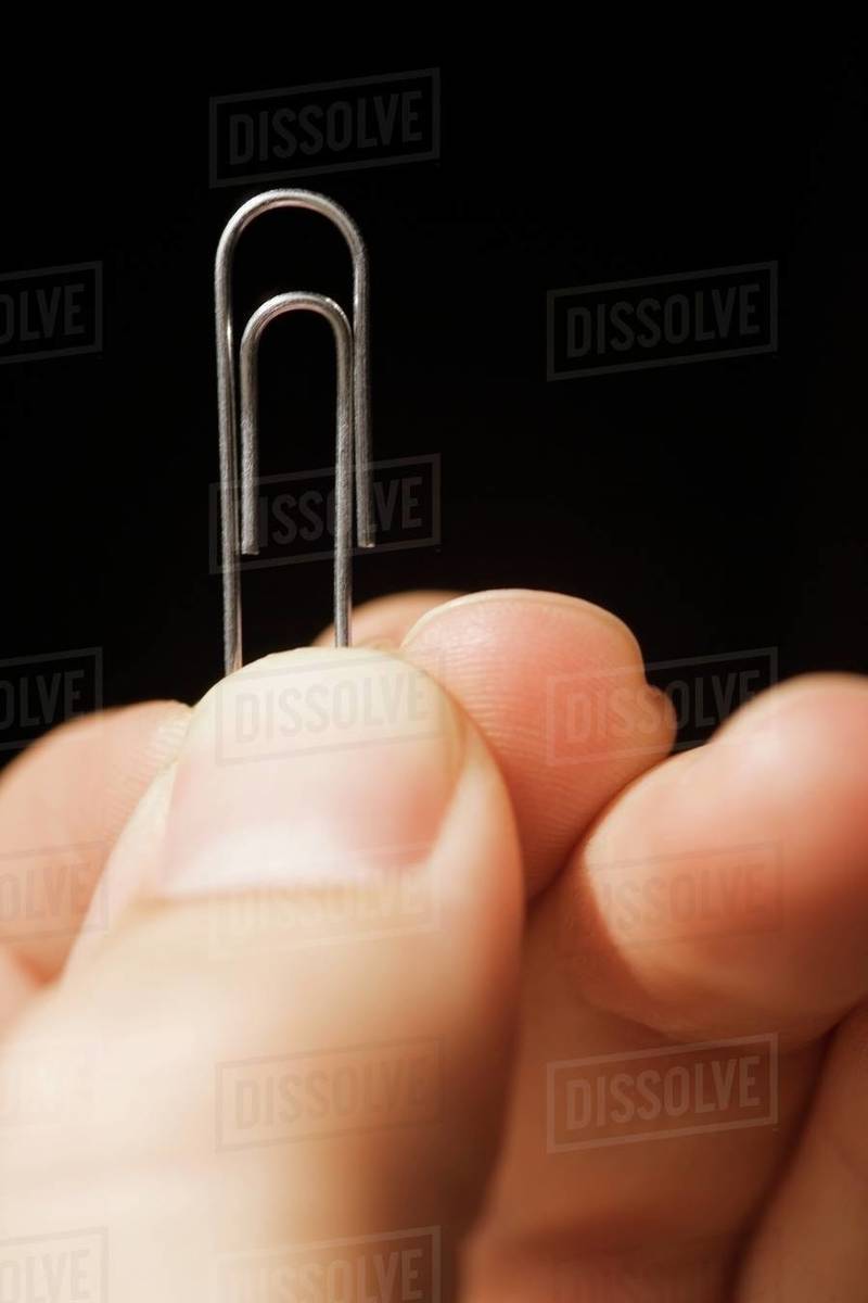 Person Holding Up A Paperclip - Stock Photo - Dissolve