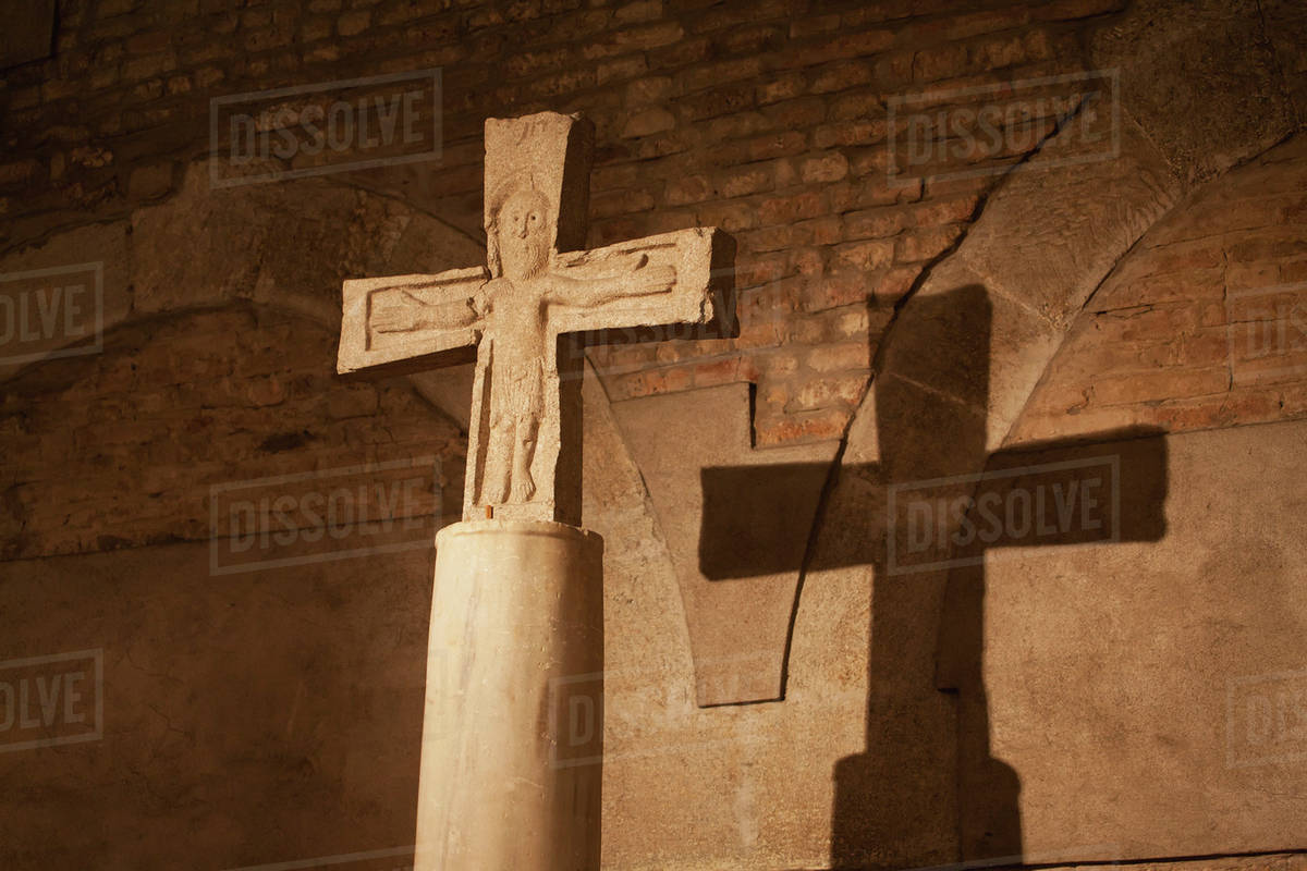 Close up of stone cross/crucifix with a shadow on brick wall in ...
