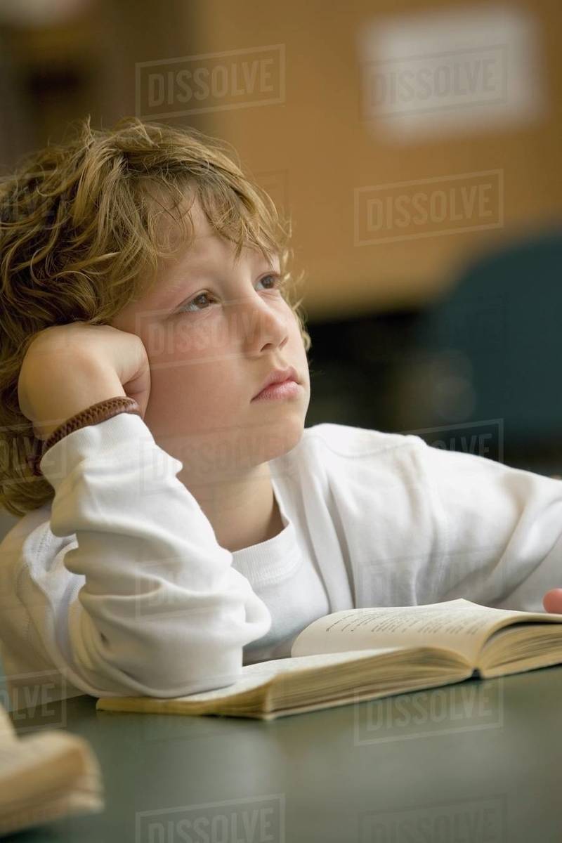 Young Boy Pondering Over Book - Royalty-free Stock Photo | Dissolve