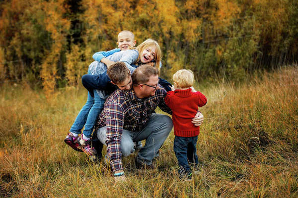 Father roughhousing with his four children outdoors in a city park in ...