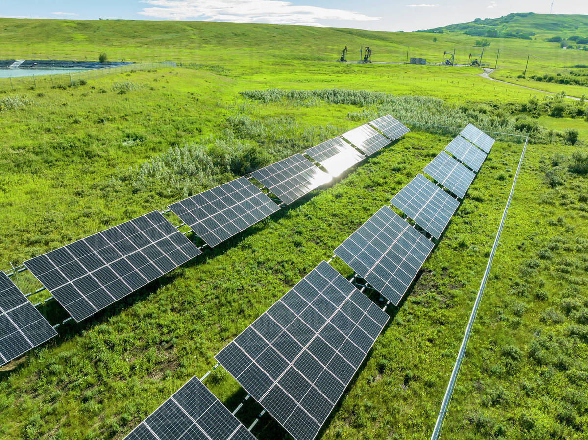 Two rows of solar panels in a green field with rolling hills in the ...