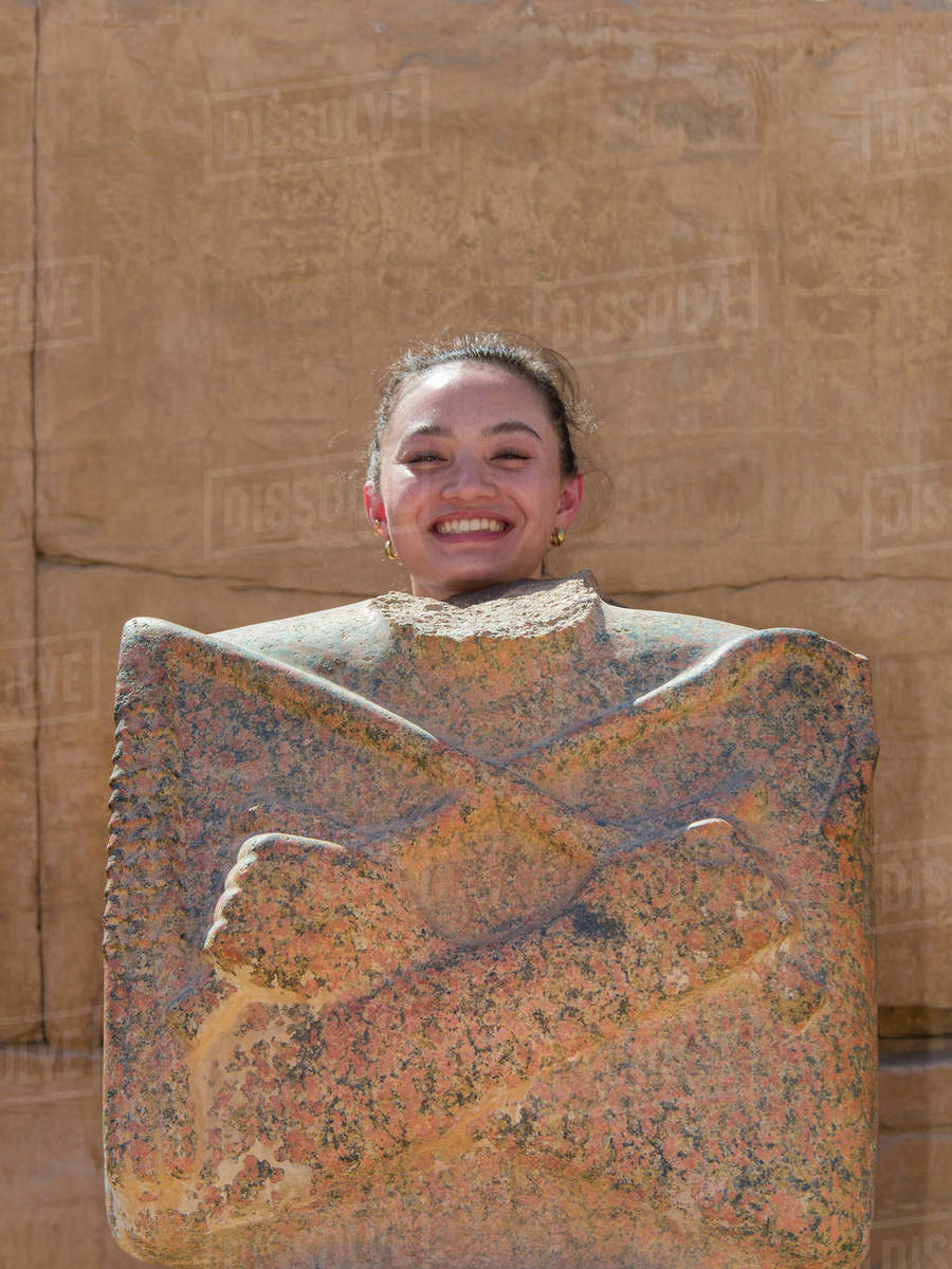 Girl posing as ancient Egyptian god with headless statue at the Karnak ...