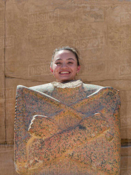 Girl posing as ancient Egyptian god with headless statue at the Karnak ...