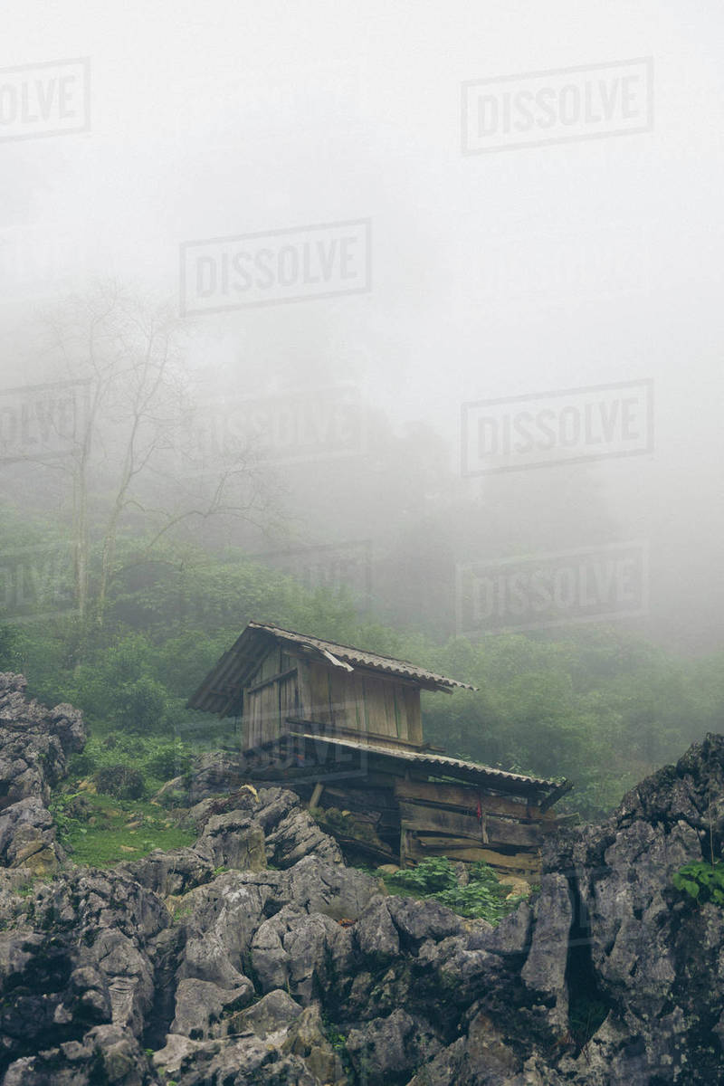 Traditional wooden structure built on a rocky terrain in the fog in a ...
