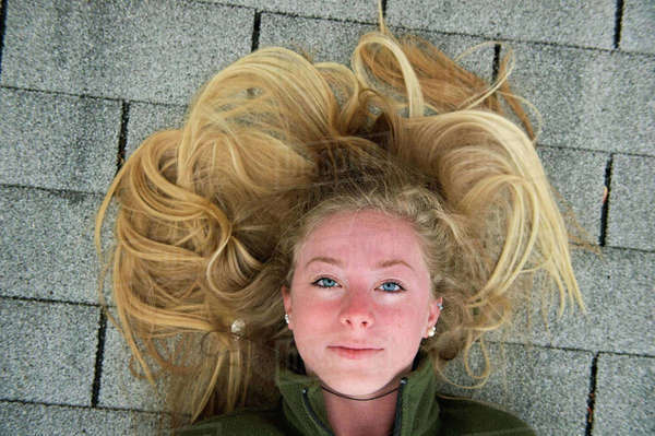 Teenage girl with long blond hair lays on shingled roof; Elkhorn ...