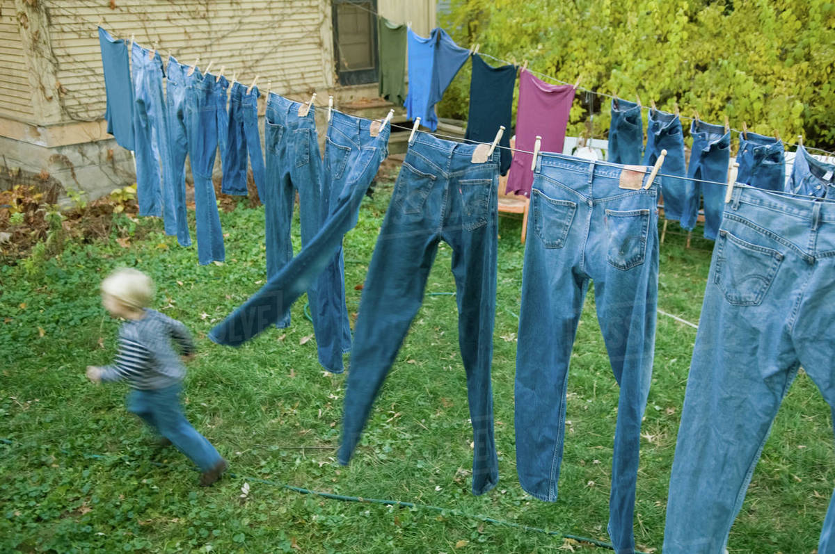 Young boy runs through jeans that hang on a clothes line; Lincoln ...