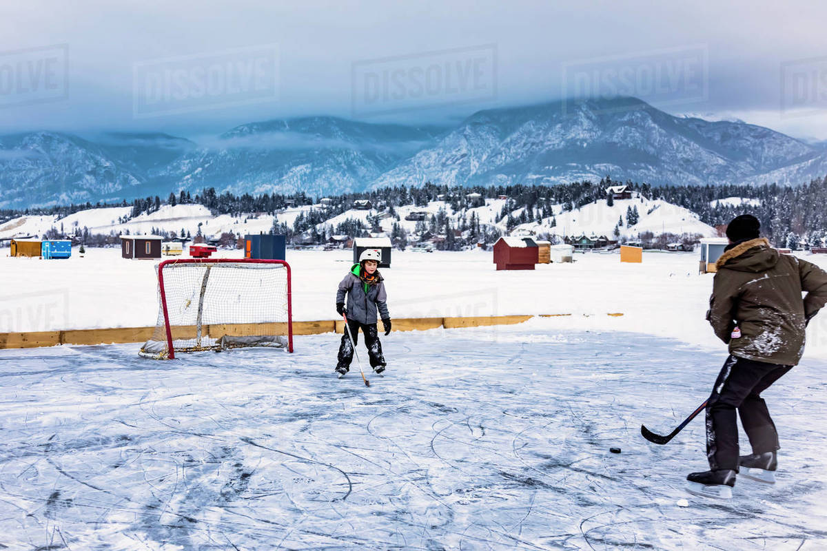 Father and his son playing hockey on a frozen Windermere Lake during ...