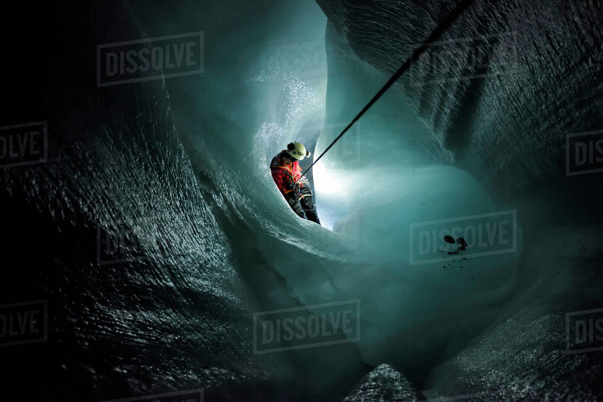 A cave explorer descends down the narrow passages of Gorner Glacier ...