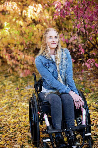 A young paraplegic woman in her wheelchair in a park on a beautiful ...