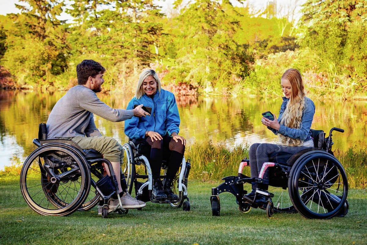 Group of three young paraplegics in their wheelchairs visiting together ...