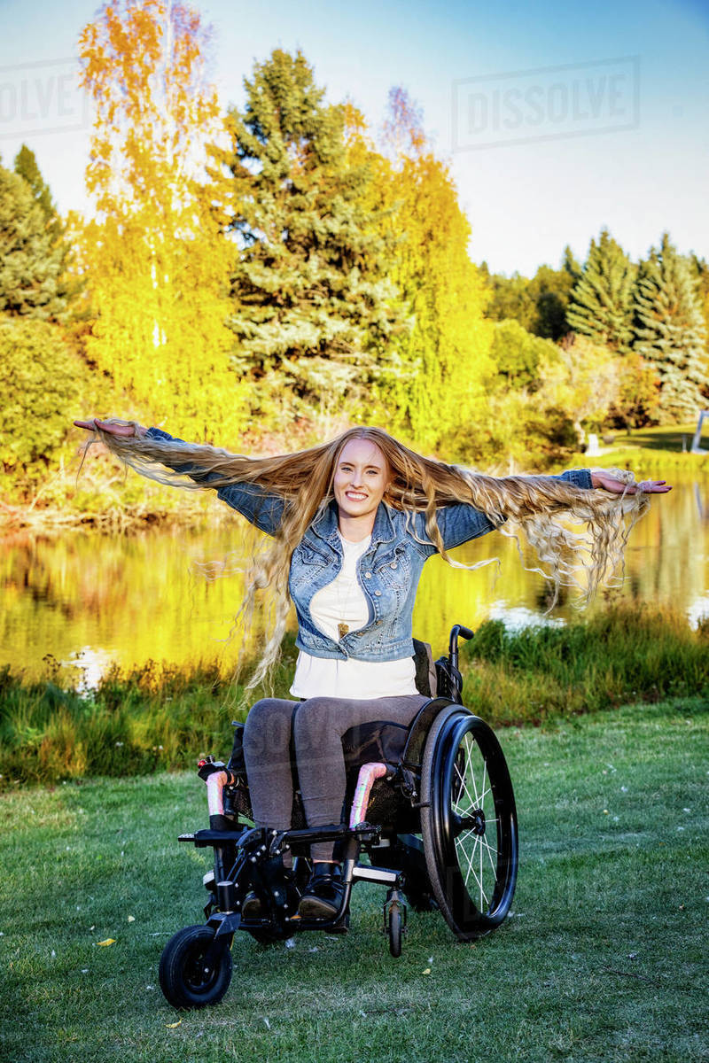 Young paraplegic woman in her wheelchair in a park on a beautiful fall ...