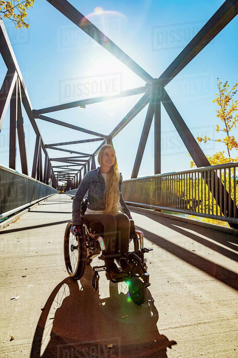 A young paraplegic woman going across a bridge using her wheelchair on ...