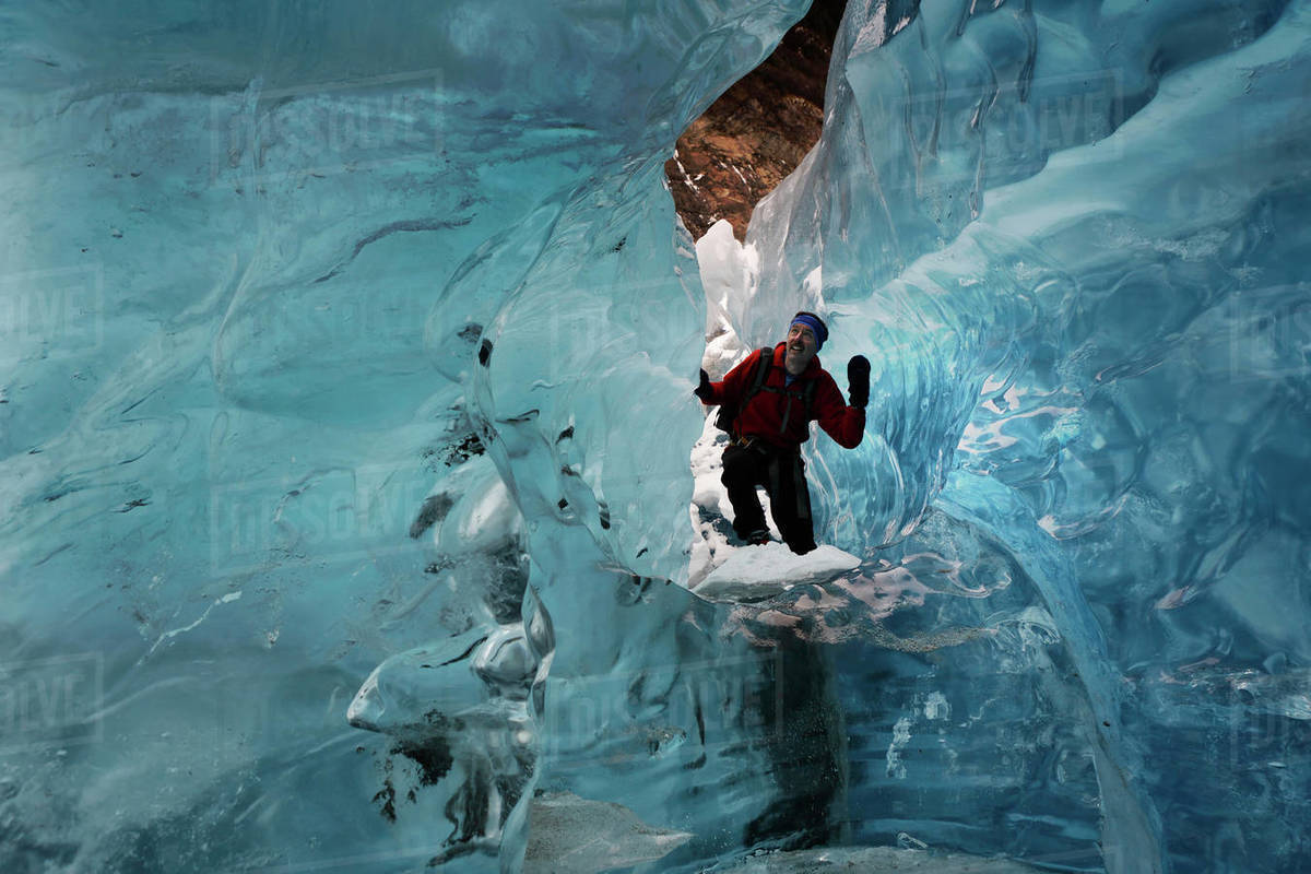 A hiker explores an ice cave recently revealed at Mendenhall Glacier ...