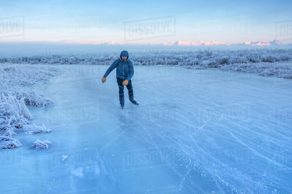 A caucasian man backcountry ice skating, nordic blading, on wild ice of ...