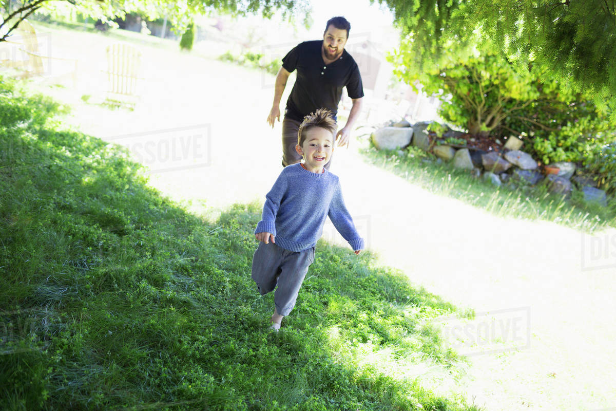 A father chases his son in a park; Victoria, British Columbia, Canada ...