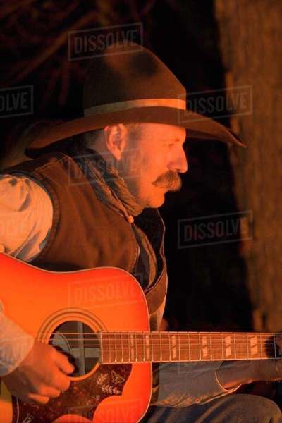 Cowboy Playing Guitar By Campfire - Royalty-free Stock Photo | Dissolve