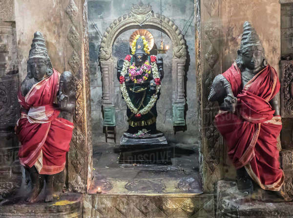 Alcove with Hindu deity statue in wall with guardian statues wrapped in ...